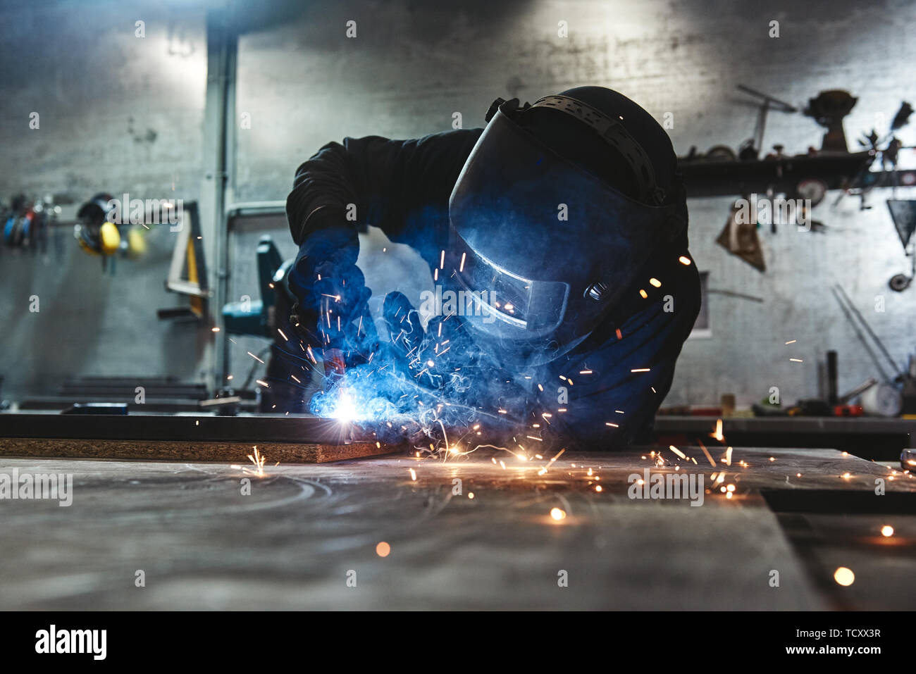 Industrial worker wearing helmet and gloves welding steel construction ...