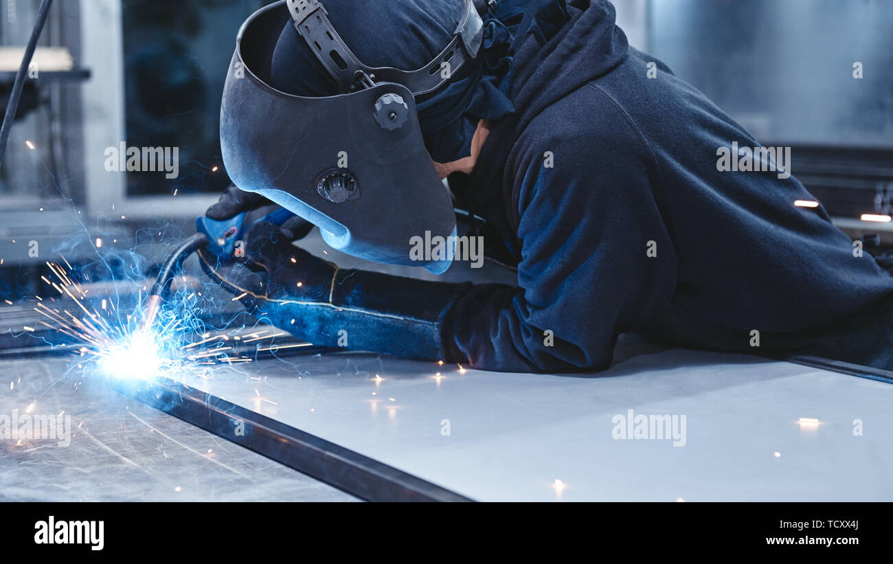 Male worker wearing helmet and gloves welding steel construction at the ...