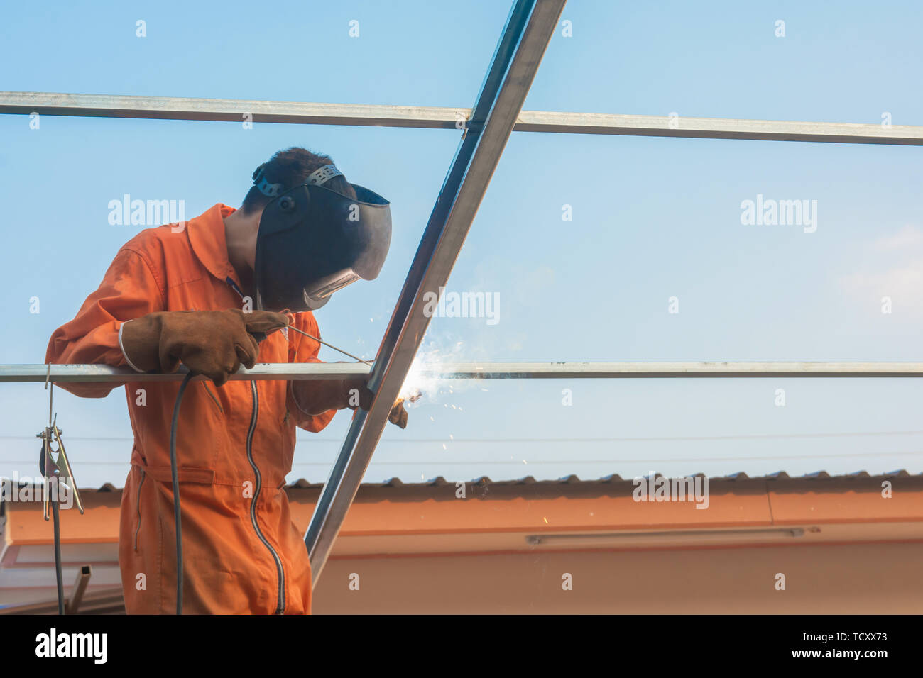 Worker welding in orange work clothes welding For roof truss Stock ...