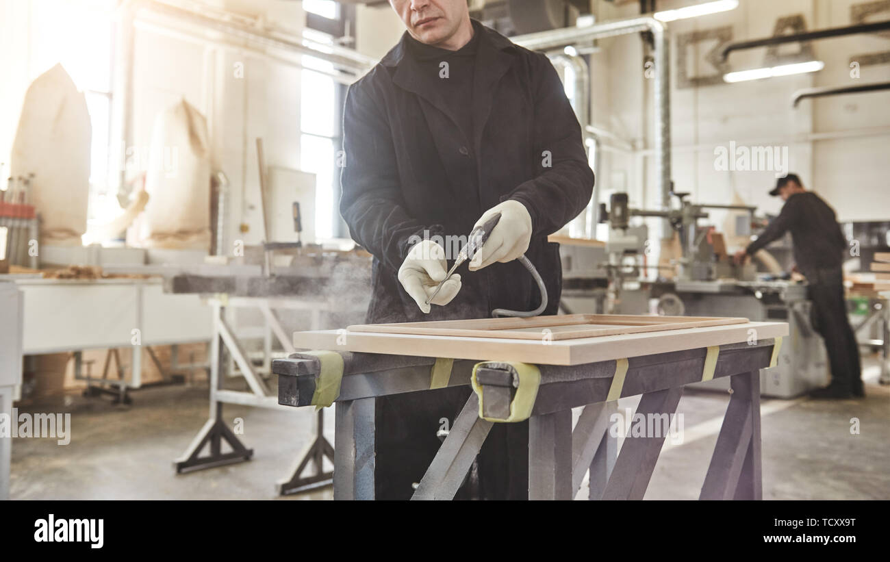 Portrait of woodworker processing the surface of the woodwork at his ...