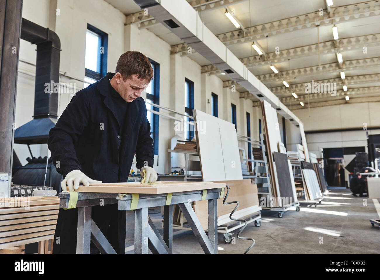 Portrait of woodworker processing the surface of the woodwork at his ...