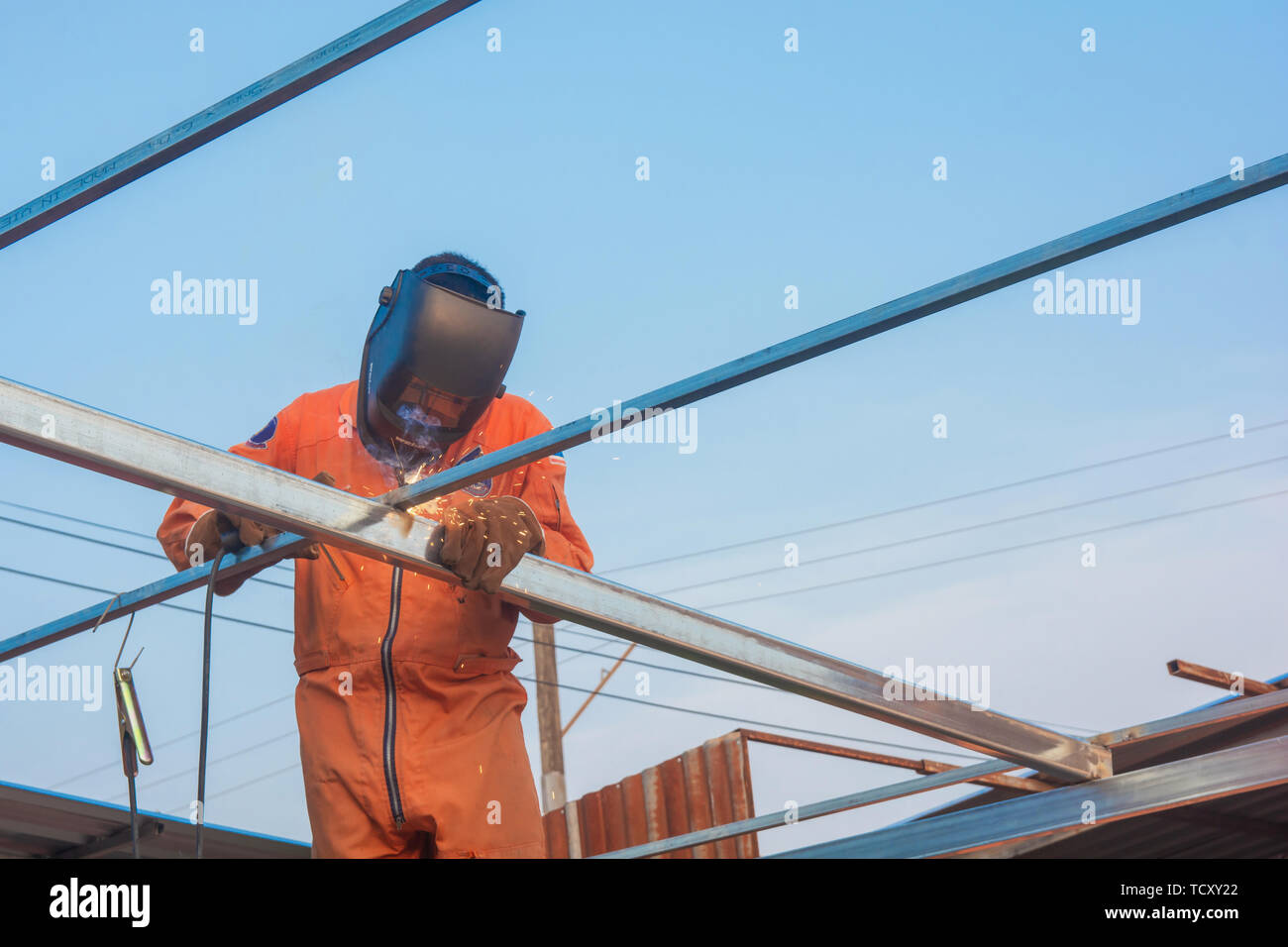 Worker welding in orange work clothes welding For roof truss Stock ...