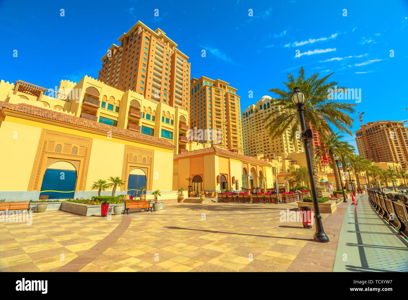 Benches and palm trees along marina walkway promenade in Porto Arabia ...