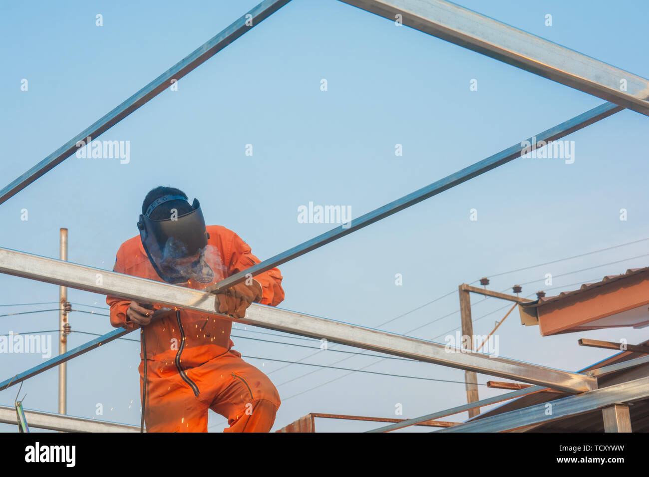 Worker welding in orange work clothes welding For roof truss Stock ...