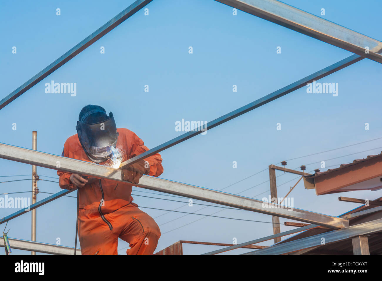 Worker welding in orange work clothes welding For roof truss Stock ...