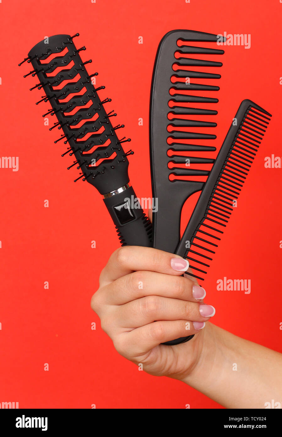 Three combs in female hand on color background Stock Photo - Alamy
