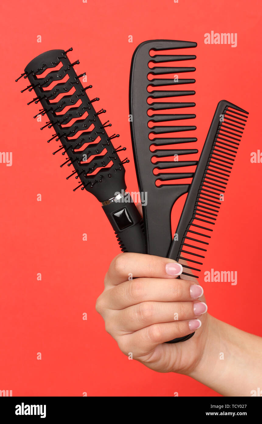 Three combs in female hand on color background Stock Photo - Alamy