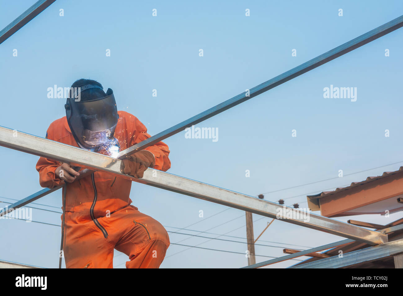 Worker welding in orange work clothes welding For roof truss Stock ...