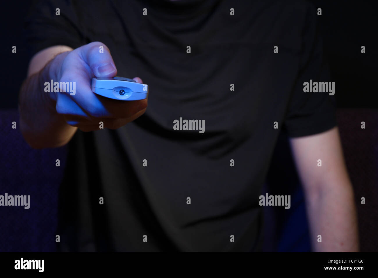 Man hand holding a TV remote control, on dark background Stock Photo ...