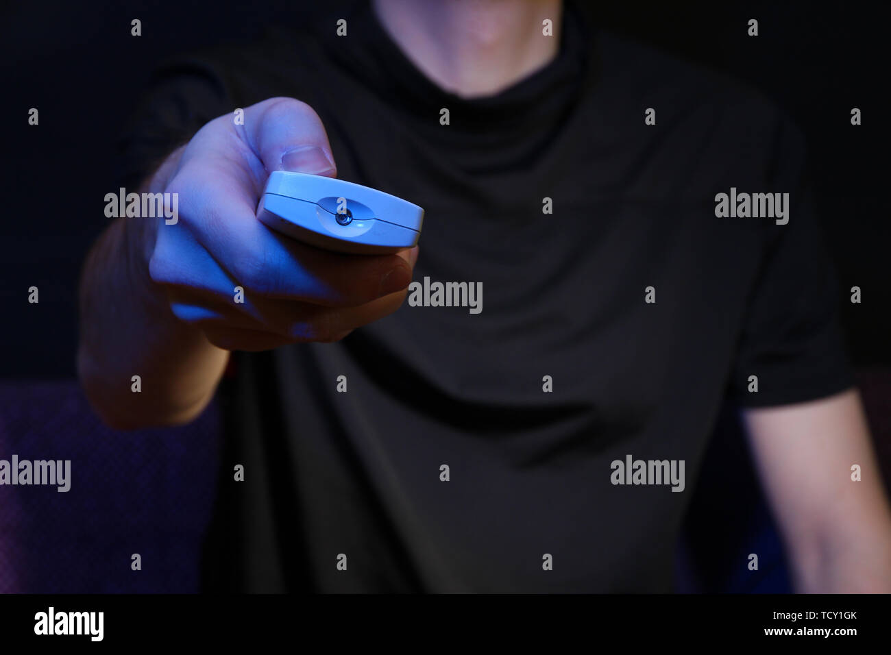 Man hand holding a TV remote control, on dark background Stock Photo ...
