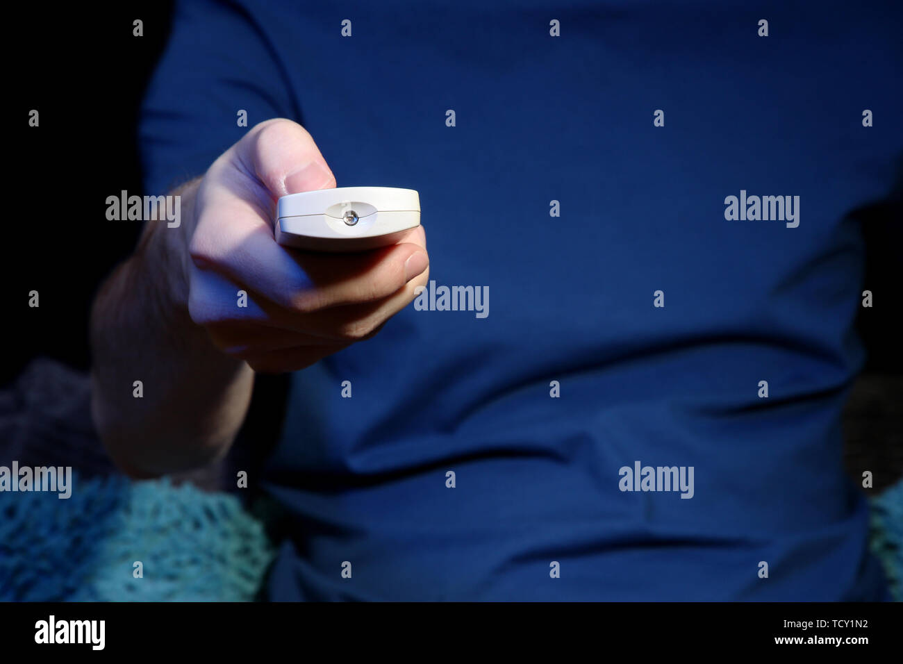 Man hand holding a TV remote control, on dark background Stock Photo ...