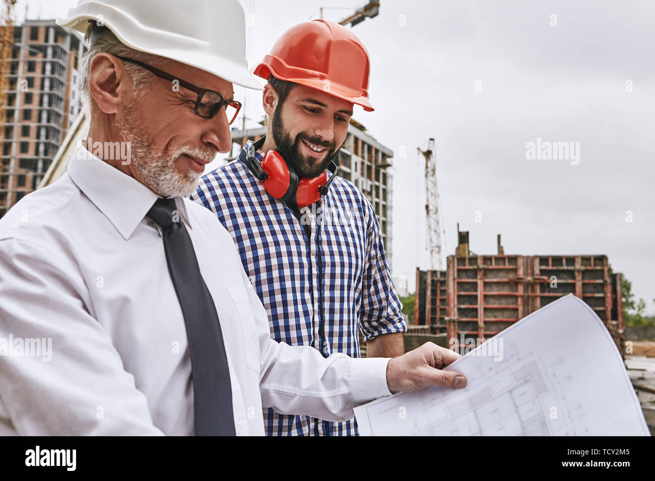 Good job! Side view of senior architect in formal wear and white helmet ...