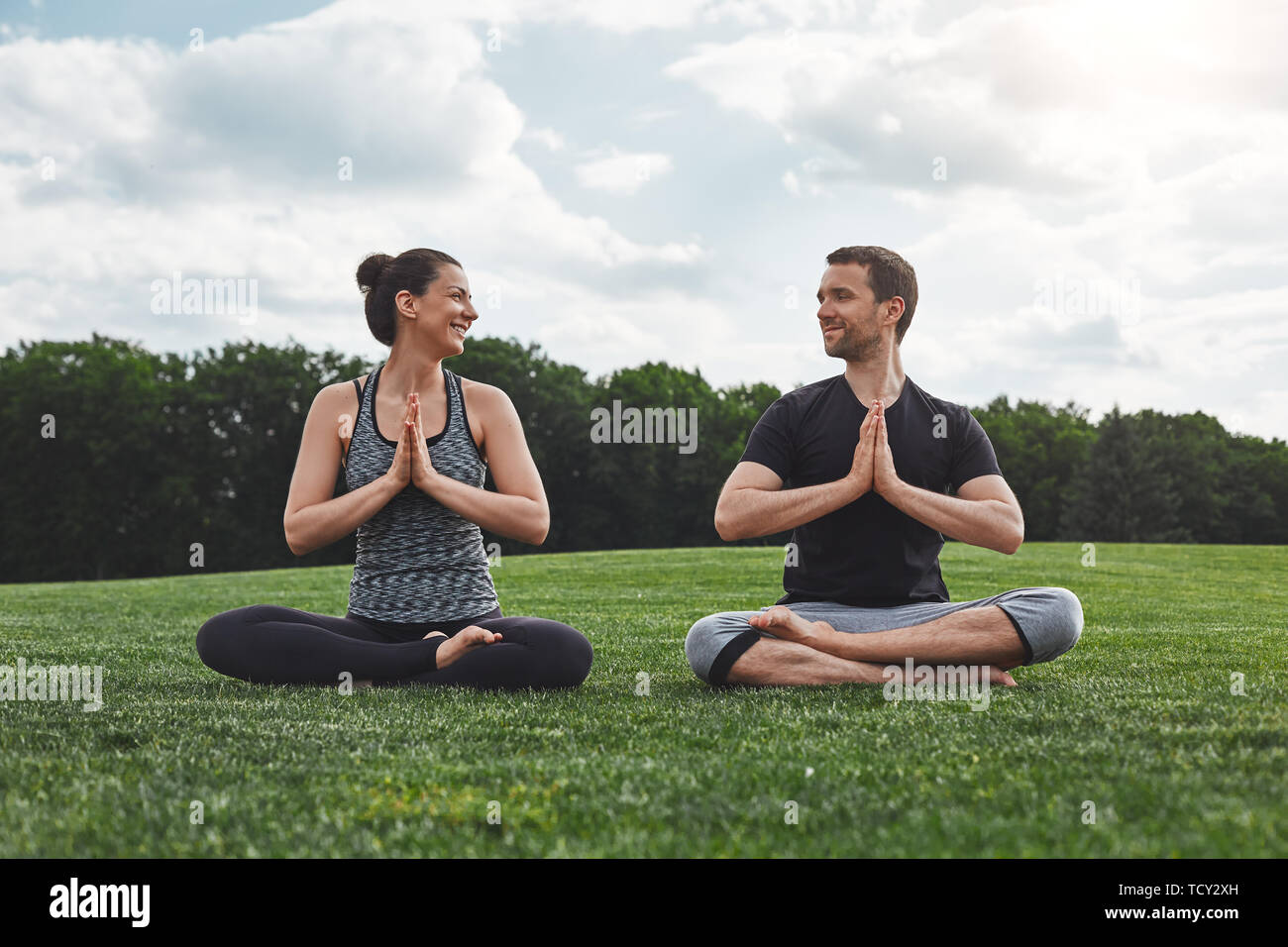 Yoga in pair. Happy couple practicing meditation exercises outdoors and ...