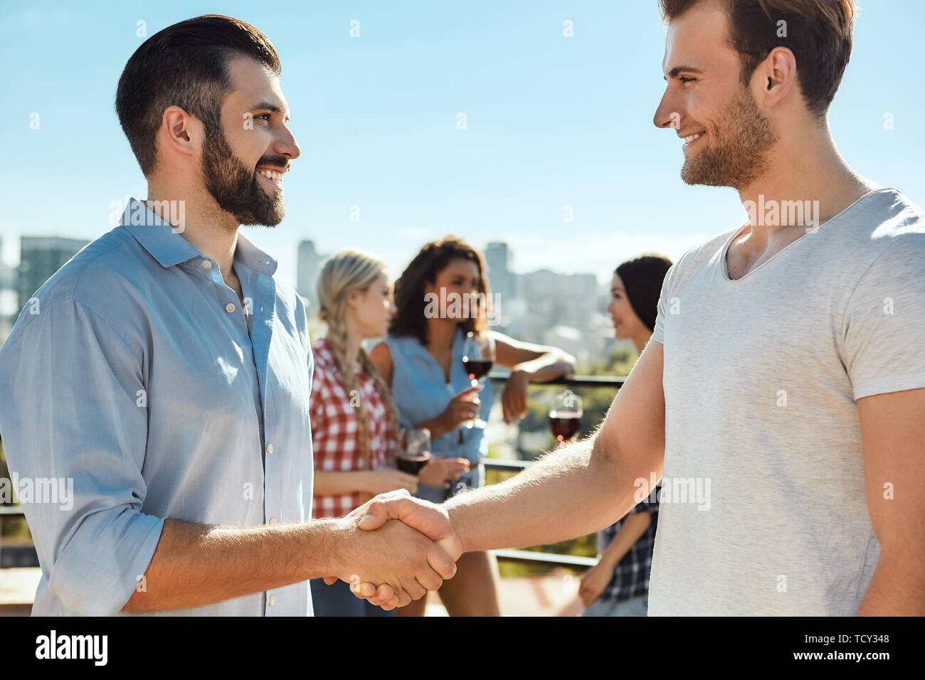 Nice to meet you! Two happy young men shaking hands and smiling while ...