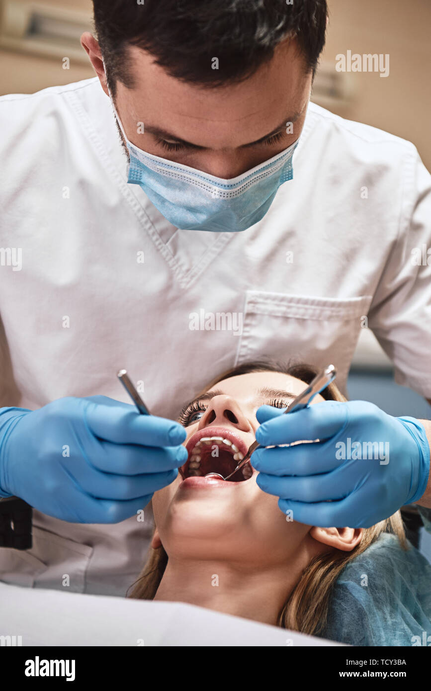 Portrait of blonde woman opening her mouth wide during inspection of ...