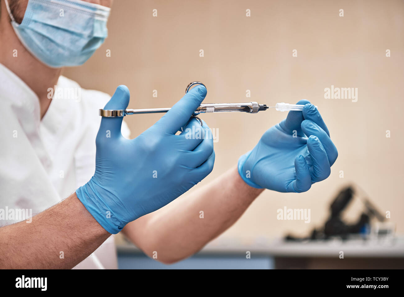 Male doctor with injection. Young dentist prepares a syringe for an ...