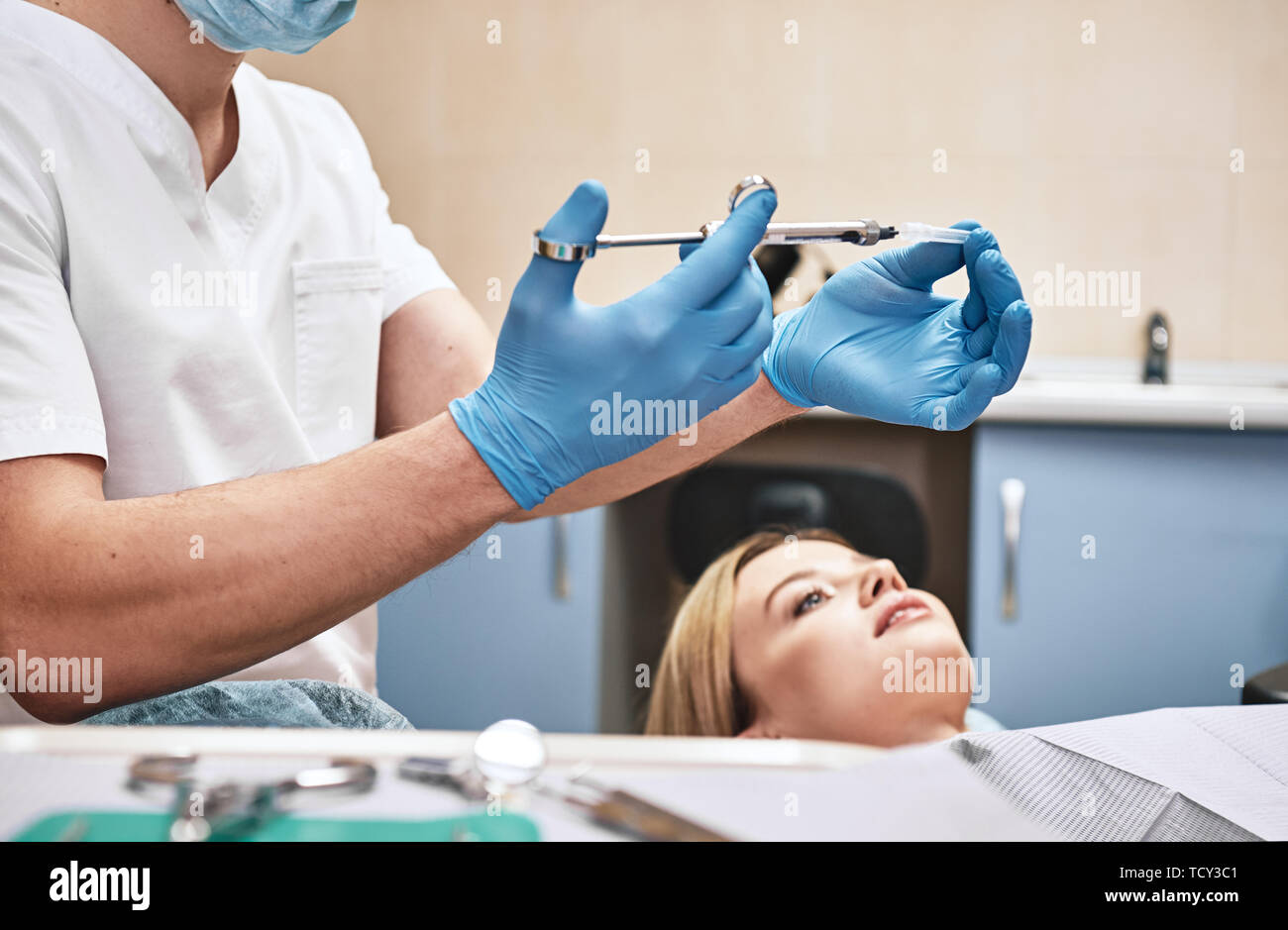Male doctor with injection. Young dentist prepares a syringe for an ...