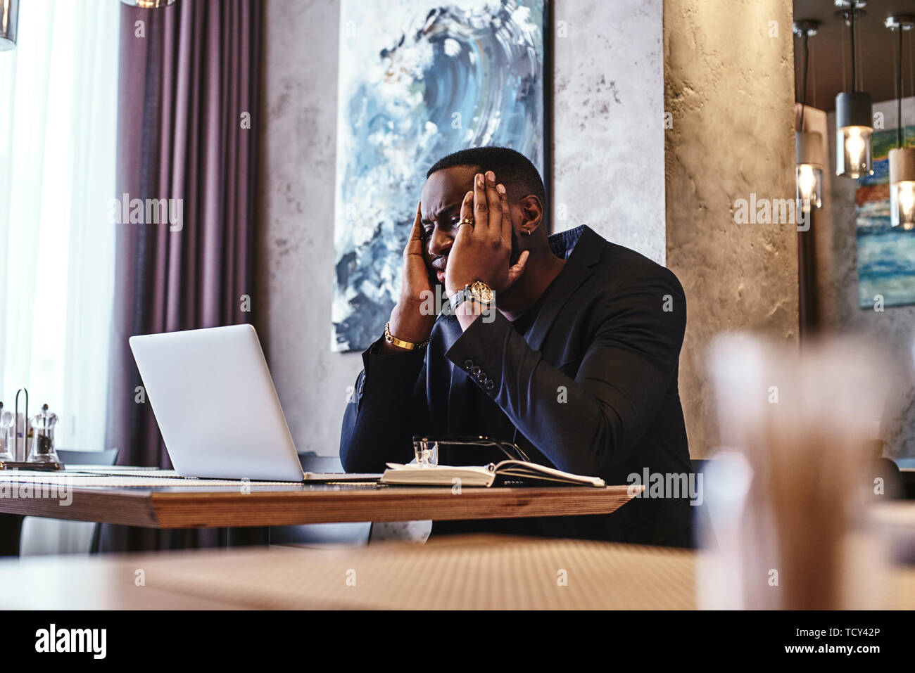 Focused African-American office manager in dark-blue jacket sitting at ...