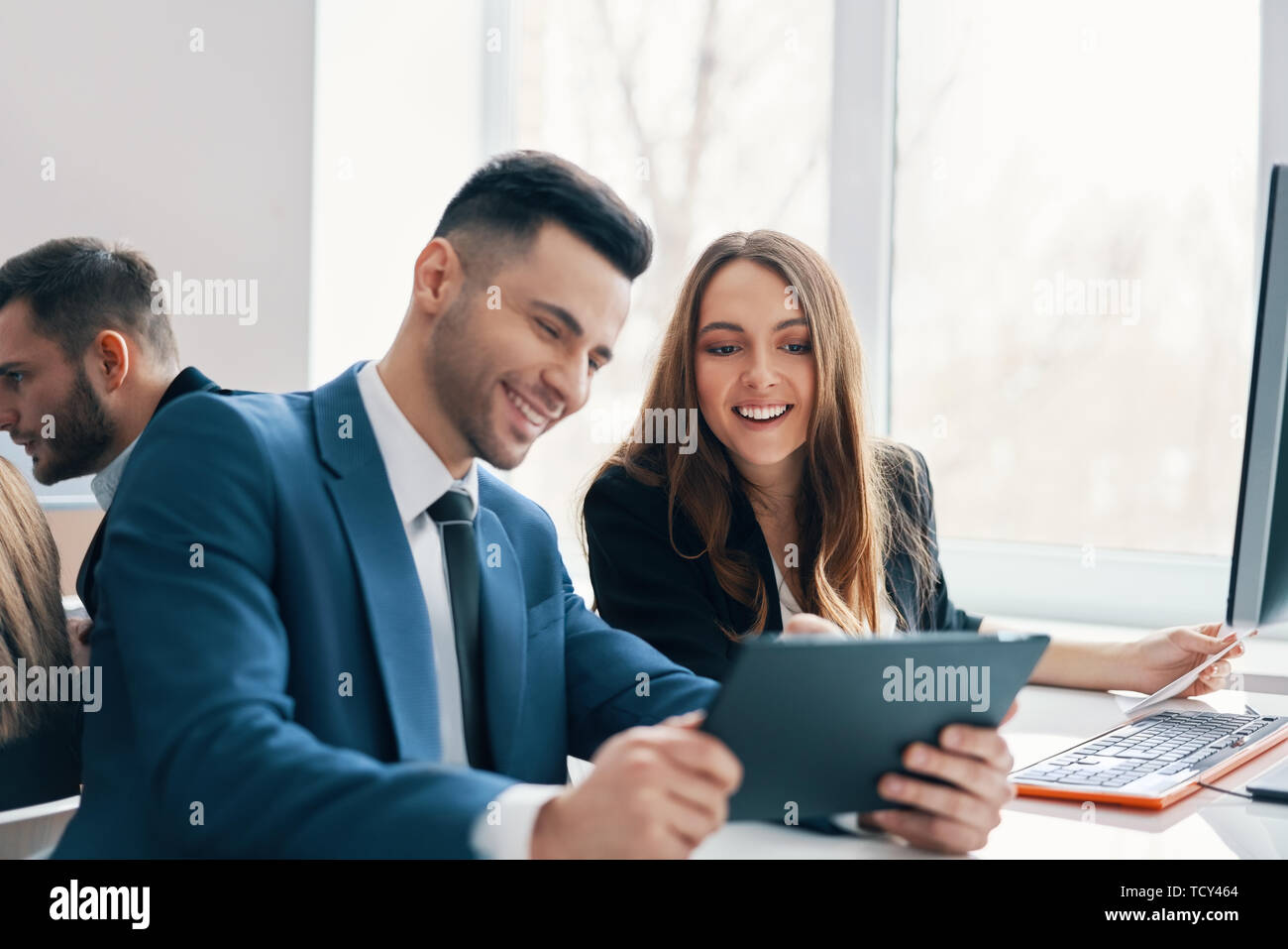 Smiling successful business people discussing ideas using digital ...