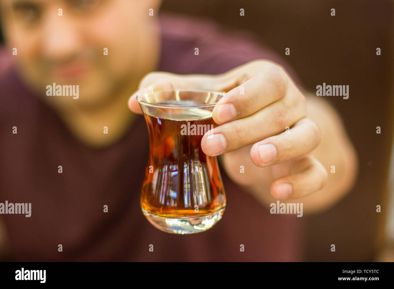 Turkish man holds out black Turkish tea in traditional glass Stock ...