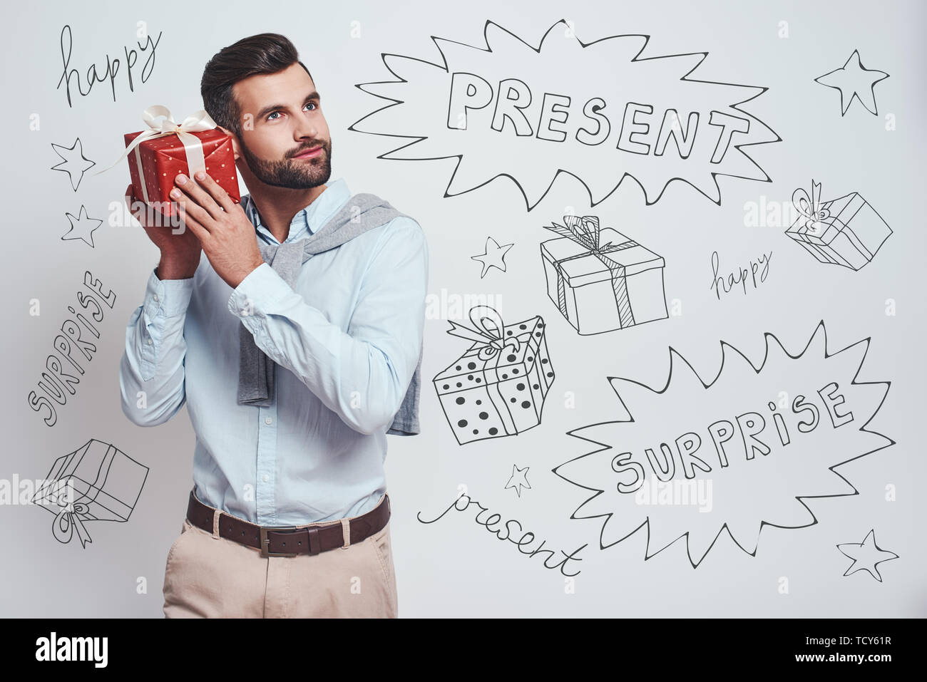 What is inside? Attractive stylish man is holding a gift box near his ...