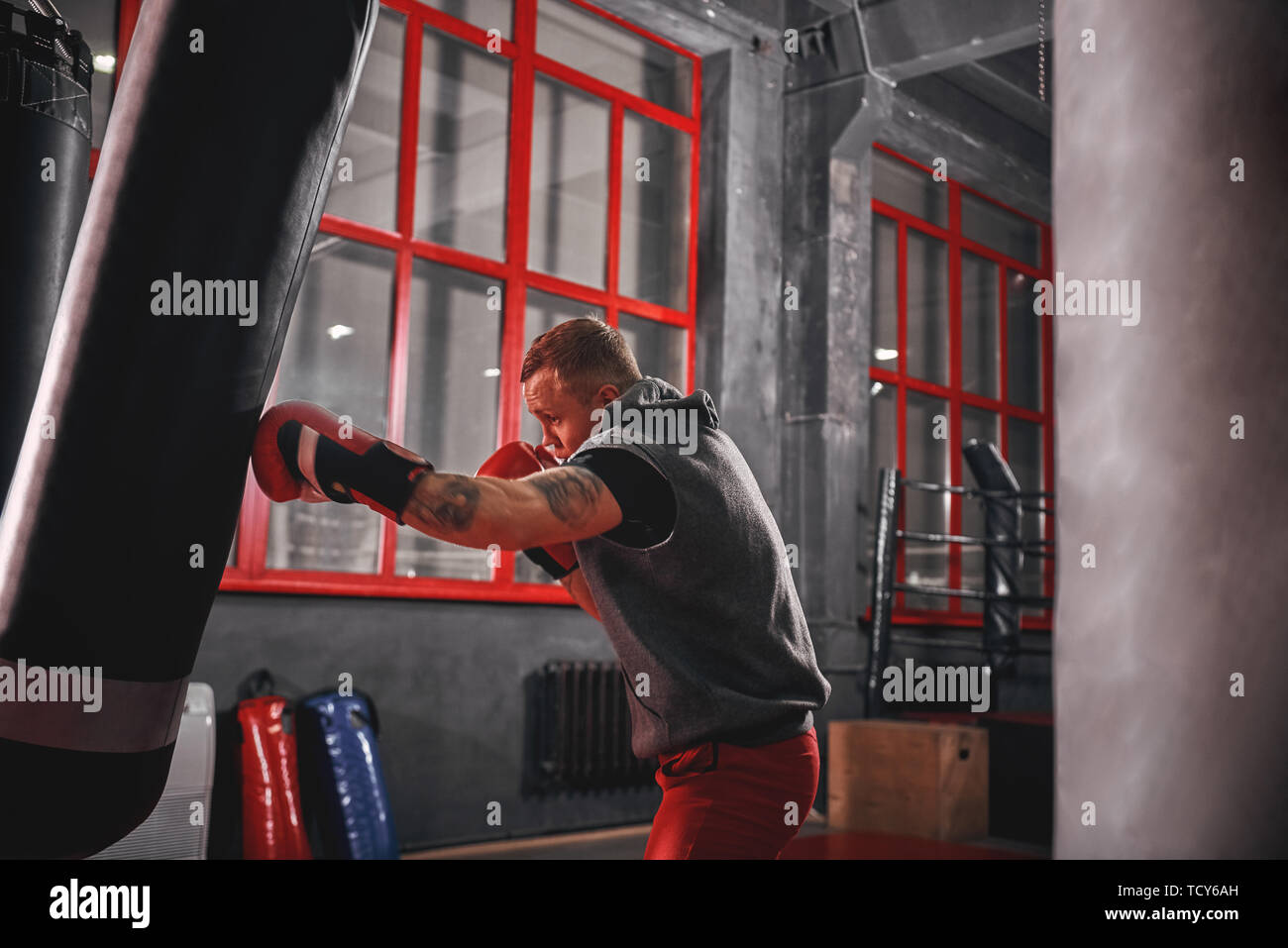 Handsome muscular sportsman in sports clothing boxing on heavy punch ...