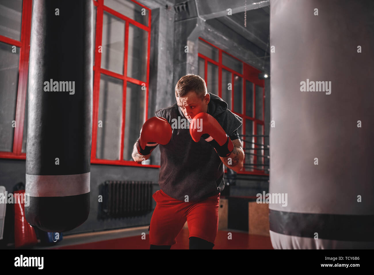 Handsome muscular sportsman in sports clothing boxing on heavy punch ...