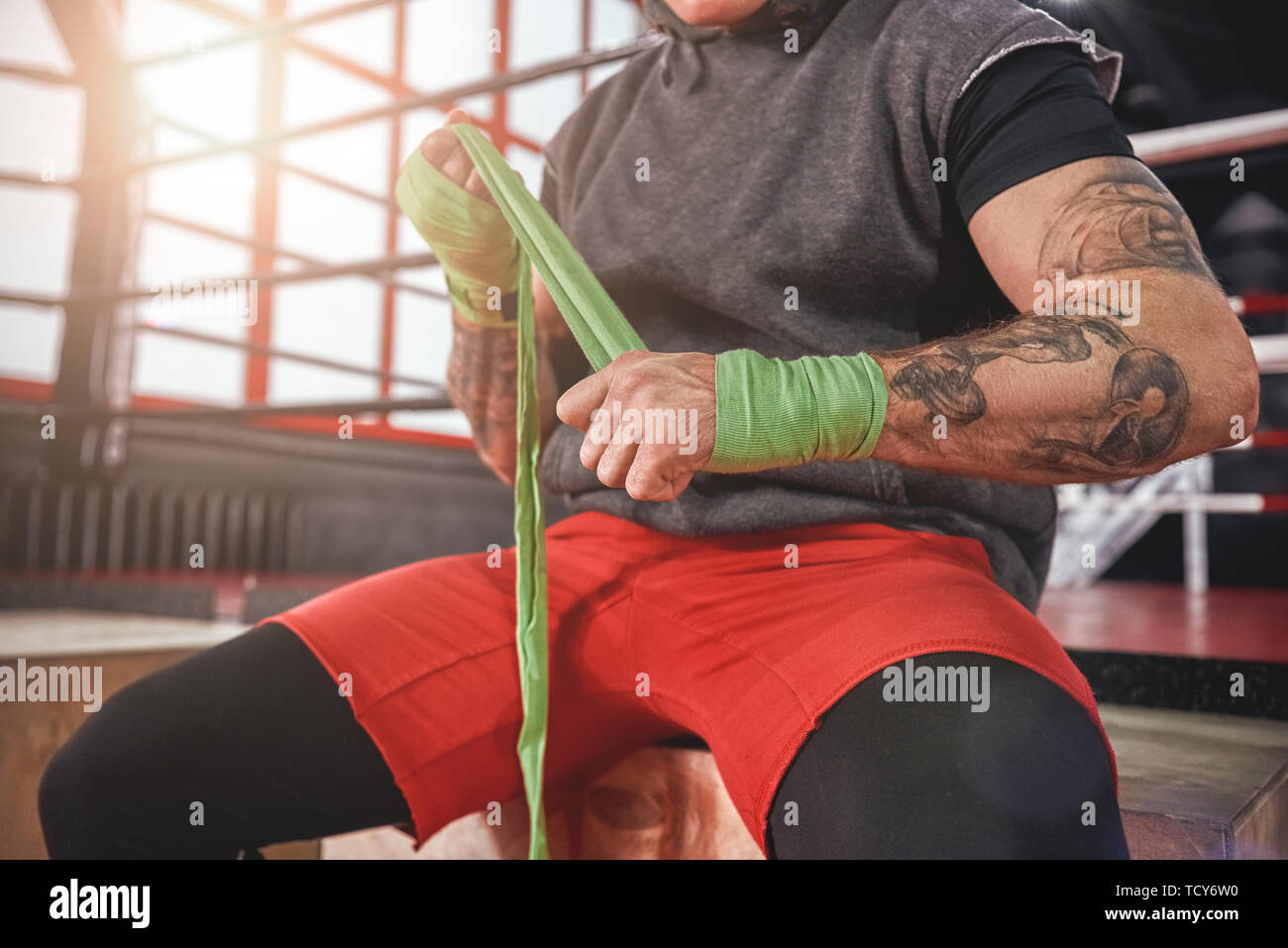 Fighting preparation. Muscular athletic man wrapping hands with green ...