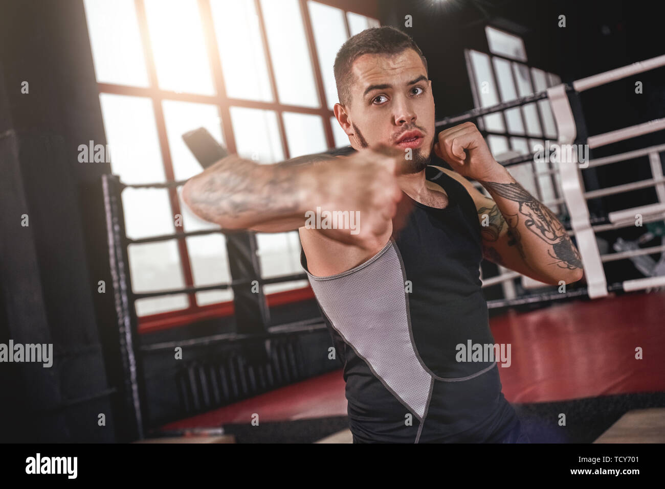Muscular athlete in sports clothing boxing side punch. Strong young man ...