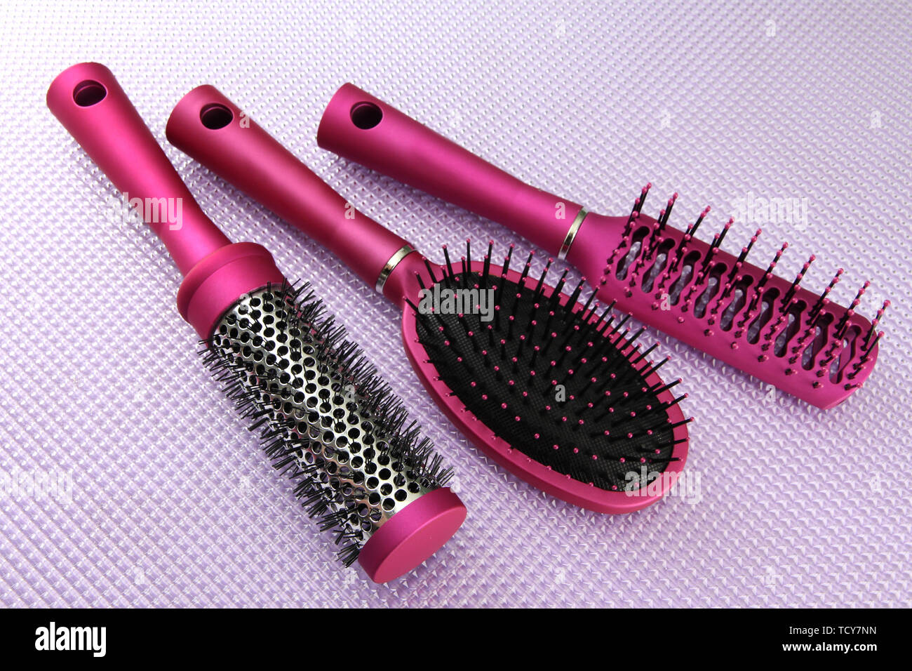 Comb brushes on purple background Stock Photo - Alamy