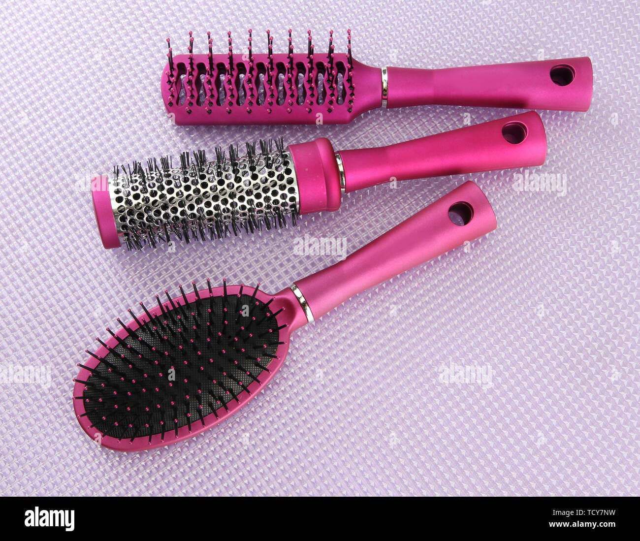 Comb brushes on purple background Stock Photo - Alamy