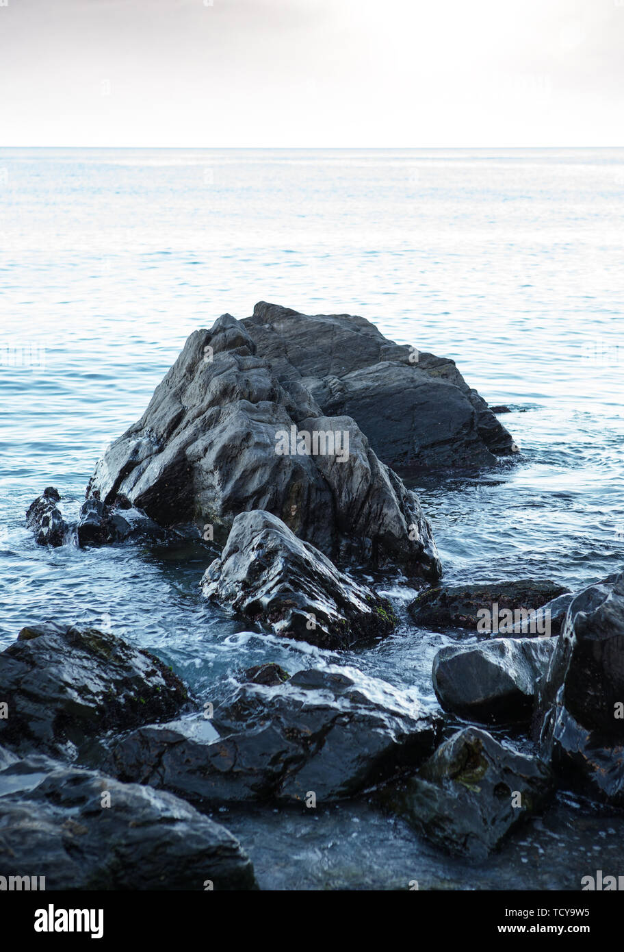 close up image in almunecar spain of large rocks going into the sea on ...