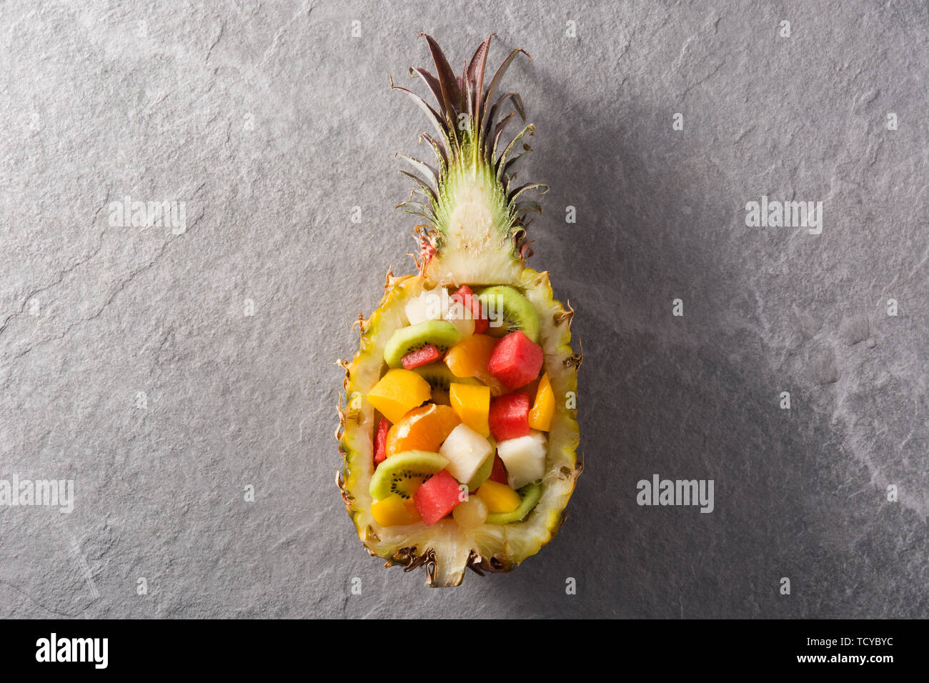 Mix fruit served inside pineapple on blue background Stock Photo - Alamy