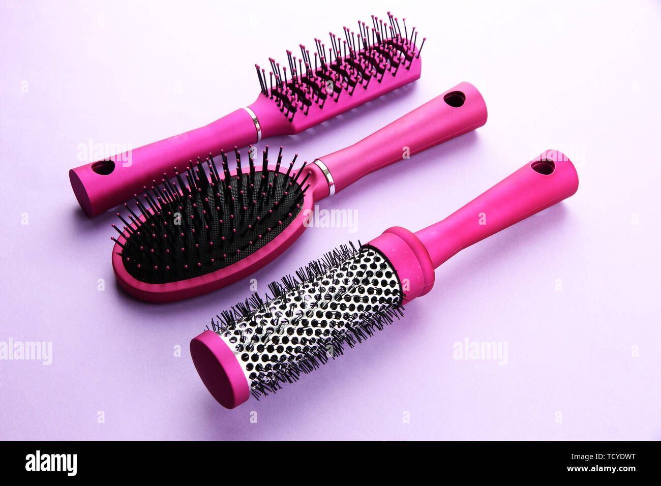Comb brushes on purple background Stock Photo - Alamy