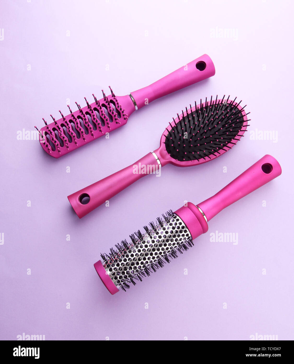 Comb brushes on purple background Stock Photo - Alamy