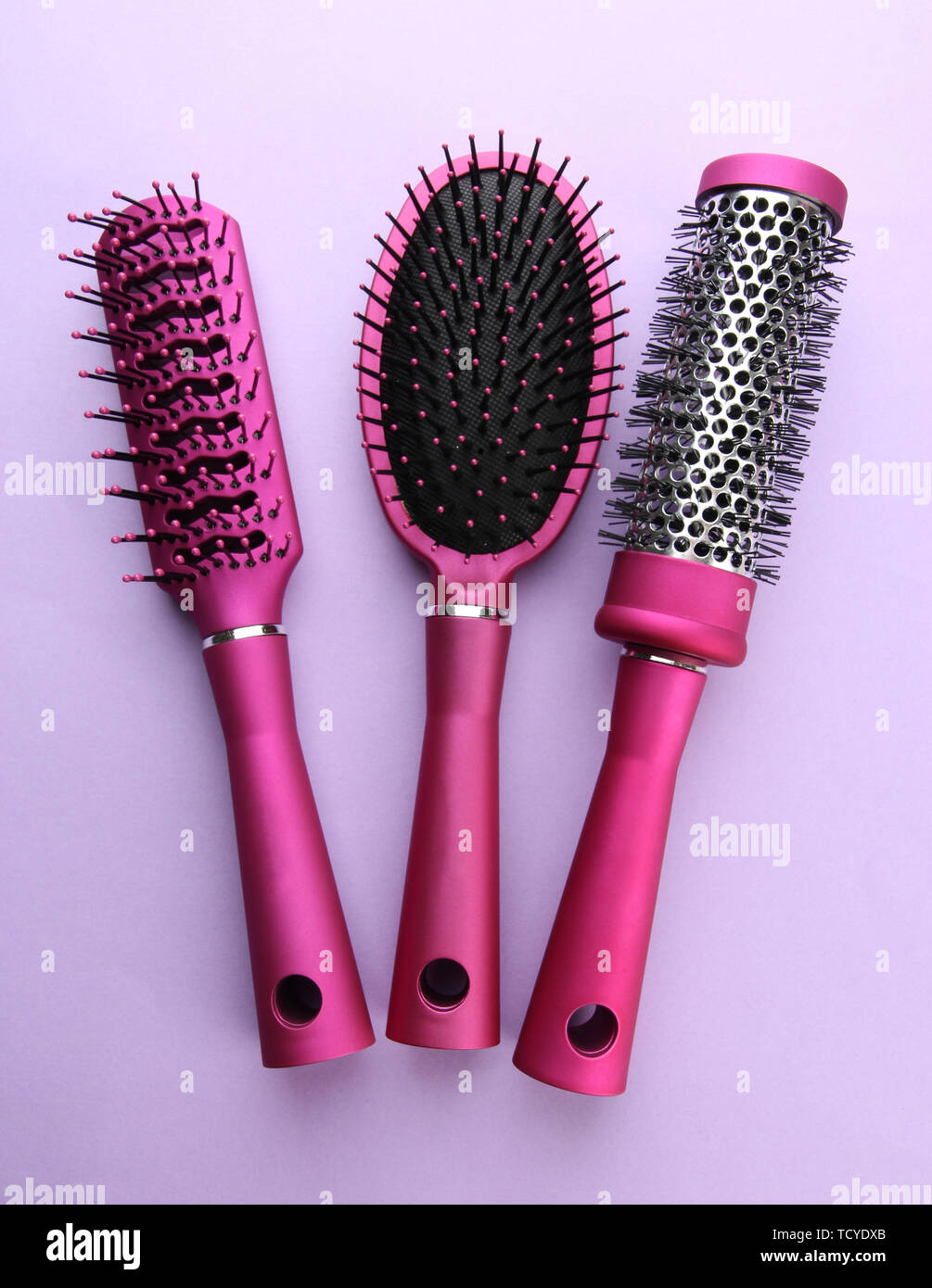 Comb brushes on purple background Stock Photo - Alamy