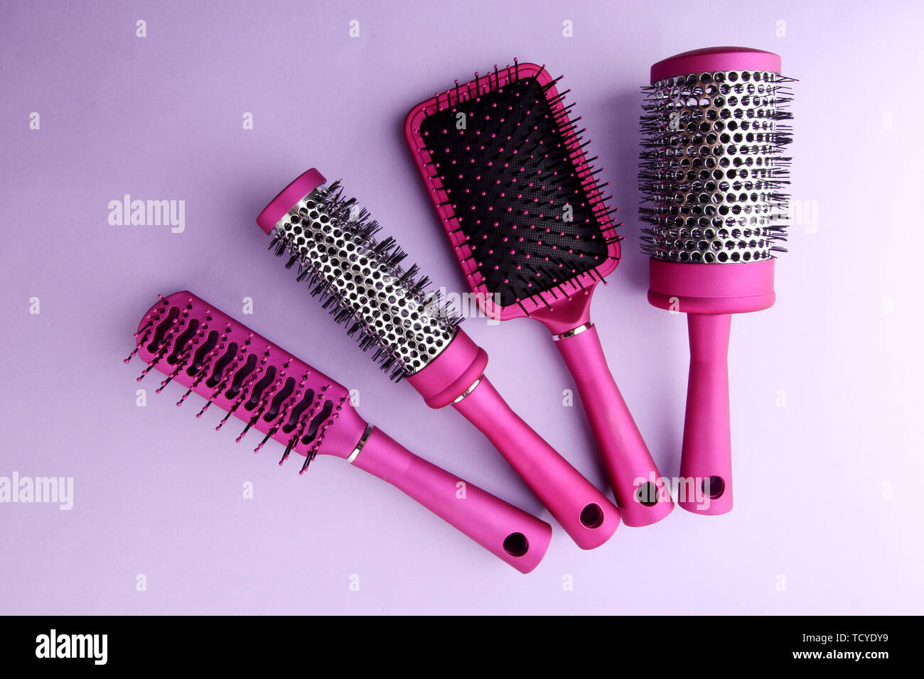 Comb brushes on purple background Stock Photo - Alamy