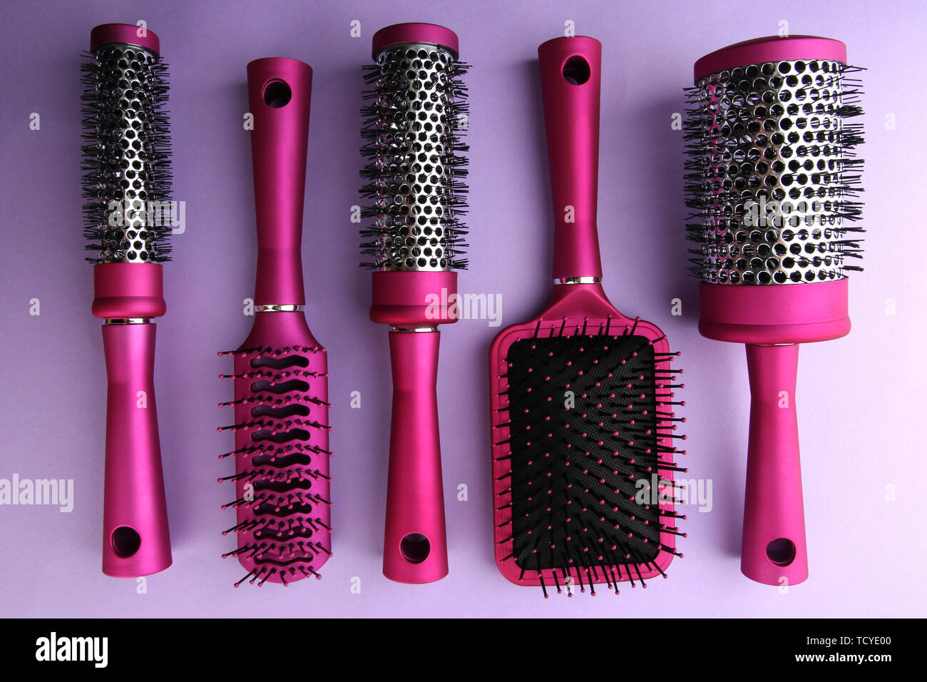 Comb brushes on purple background Stock Photo - Alamy