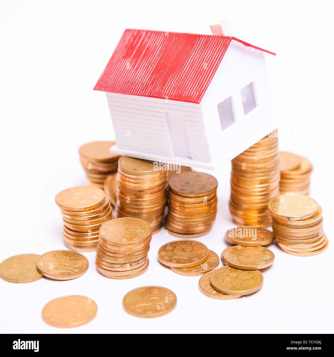 Coins and house models on white background Stock Photo - Alamy