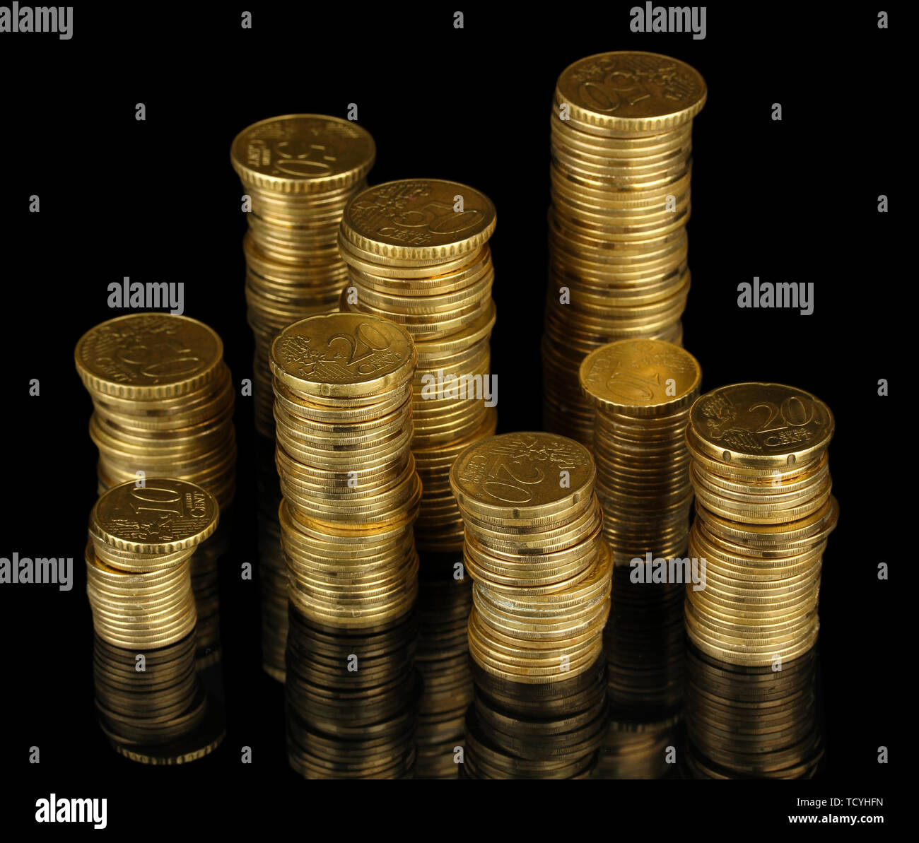 Many coins in columns isolated on black Stock Photo - Alamy