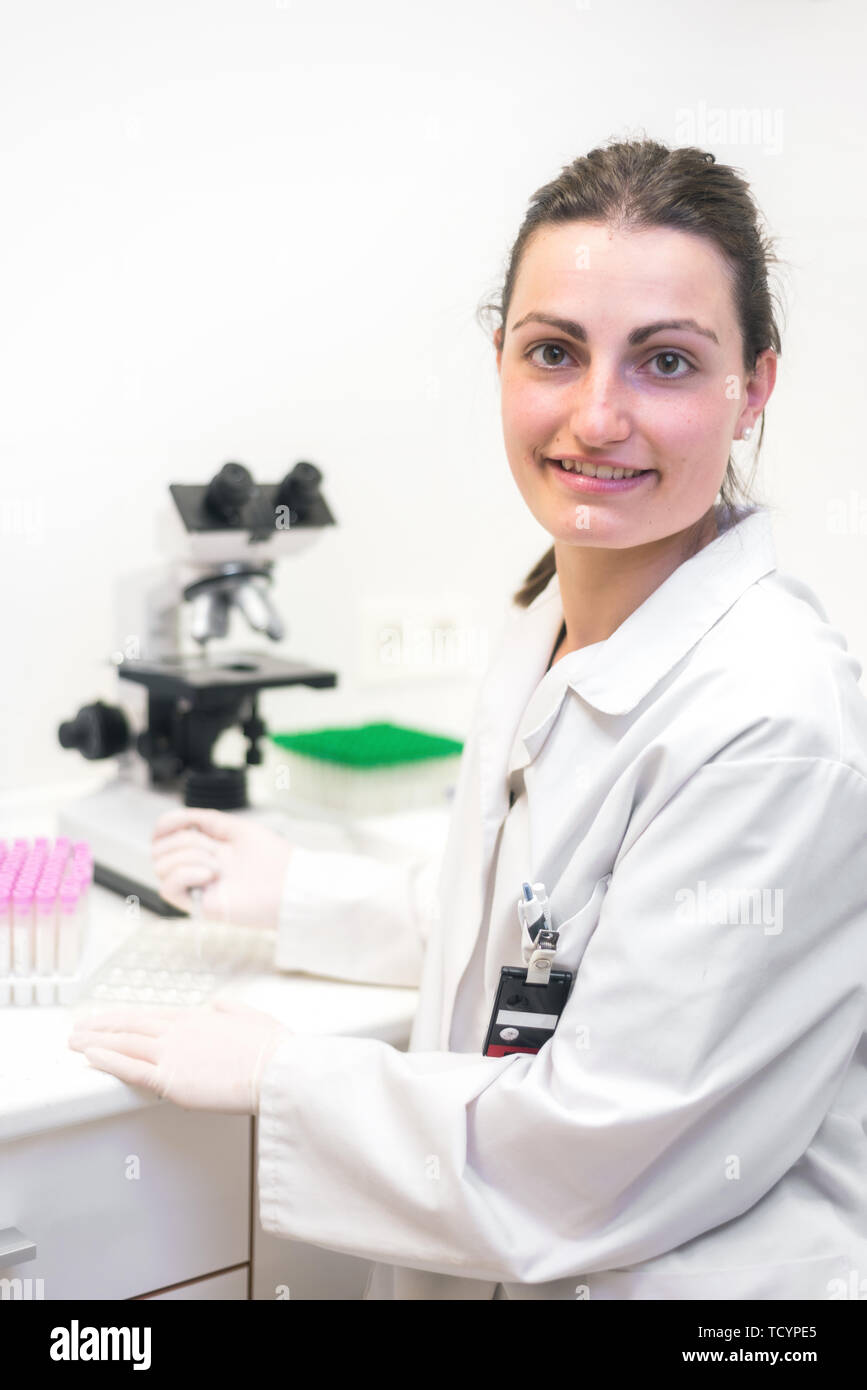 Female researcher smiling. Female researcher using microscope and ...