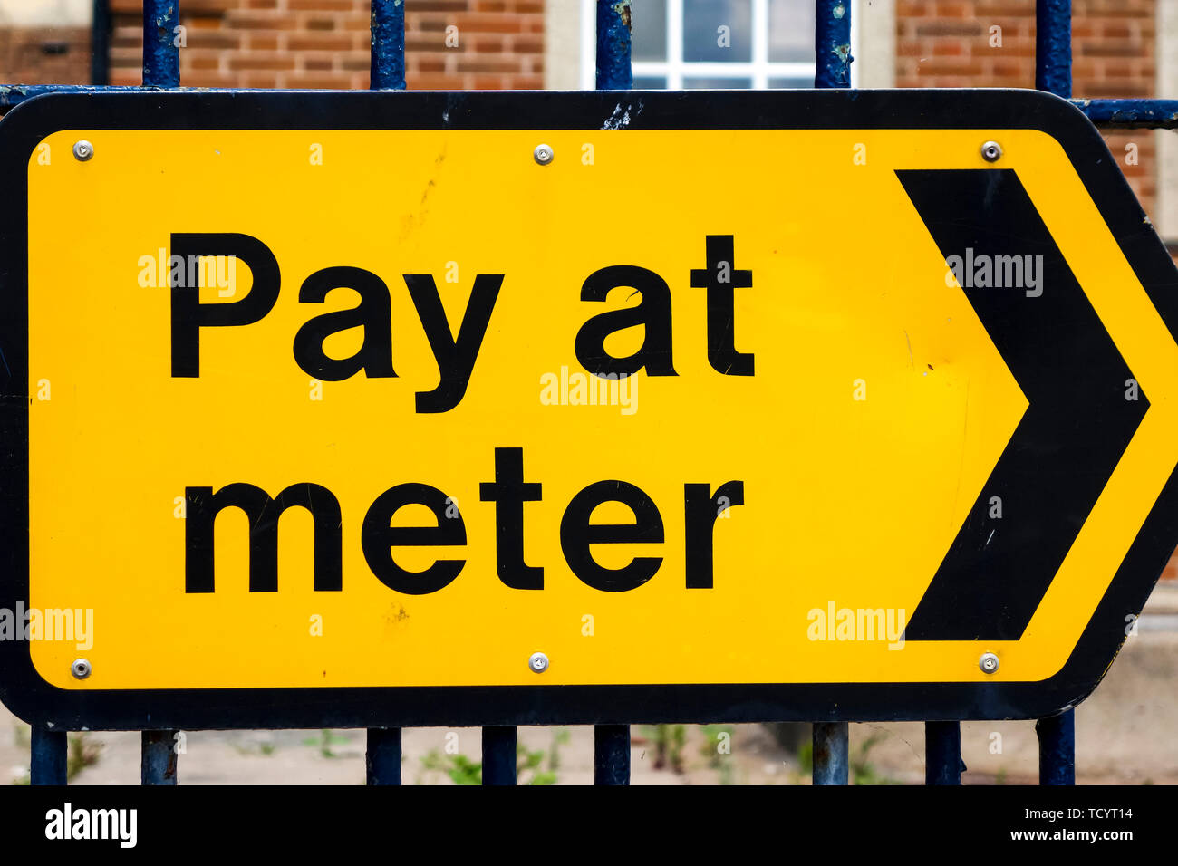Parking pay at meter sign fixed to metal railings Stock Photo - Alamy