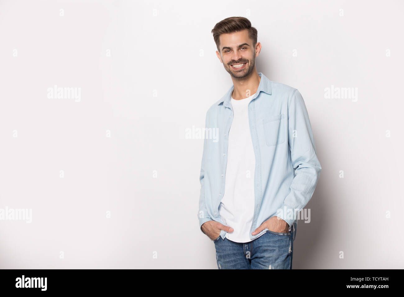 Smiling young brown-haired guy posing in studio on white Stock Photo ...