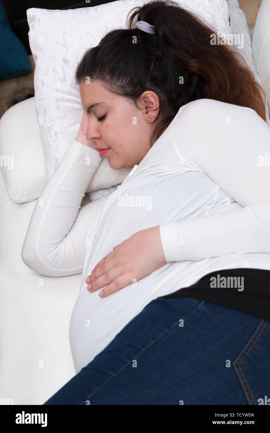 Pregnant girl taking an afternoon nap on white couch Stock Photo - Alamy