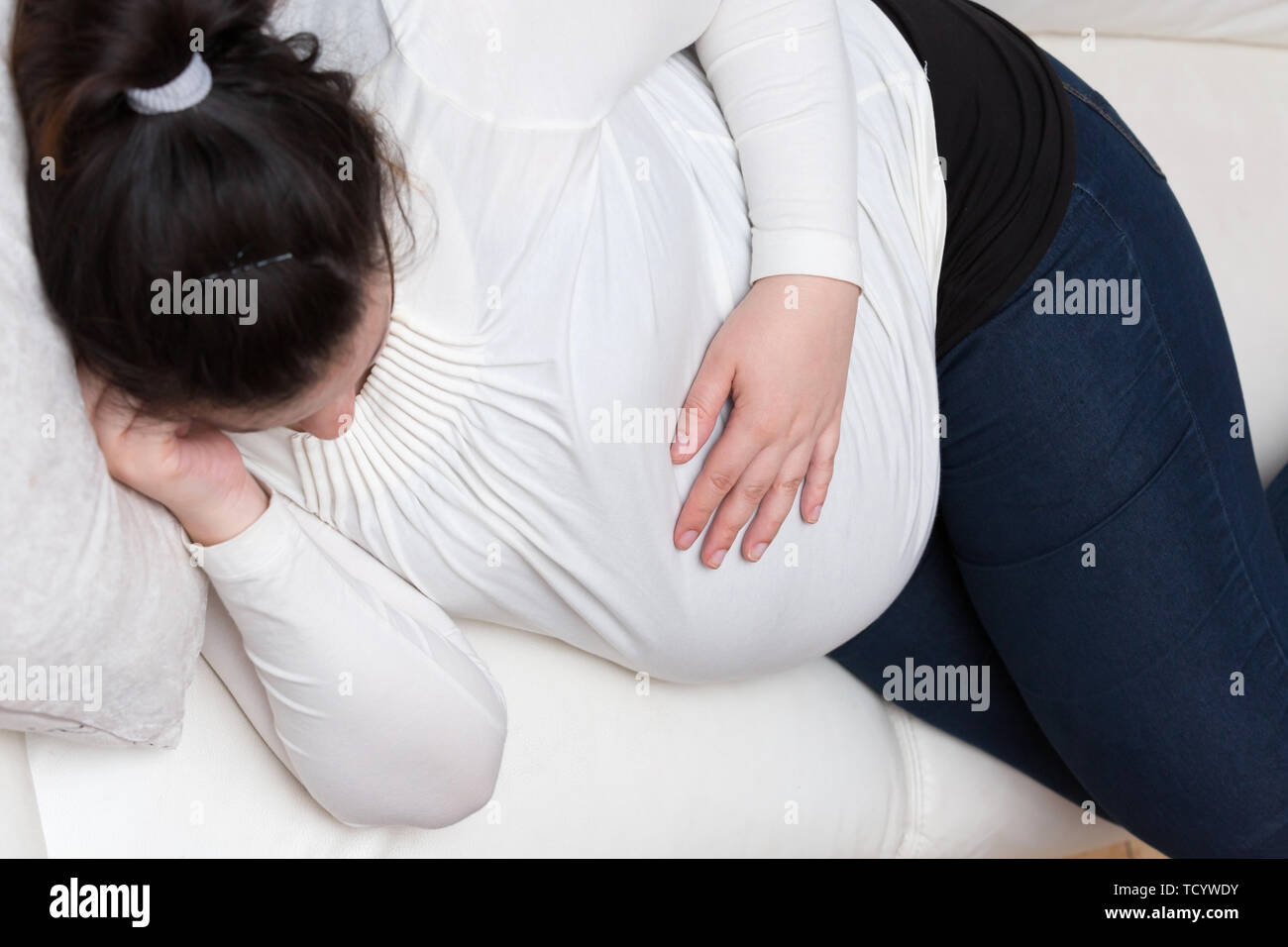 Pregnant girl taking an afternoon nap on white couch Stock Photo - Alamy
