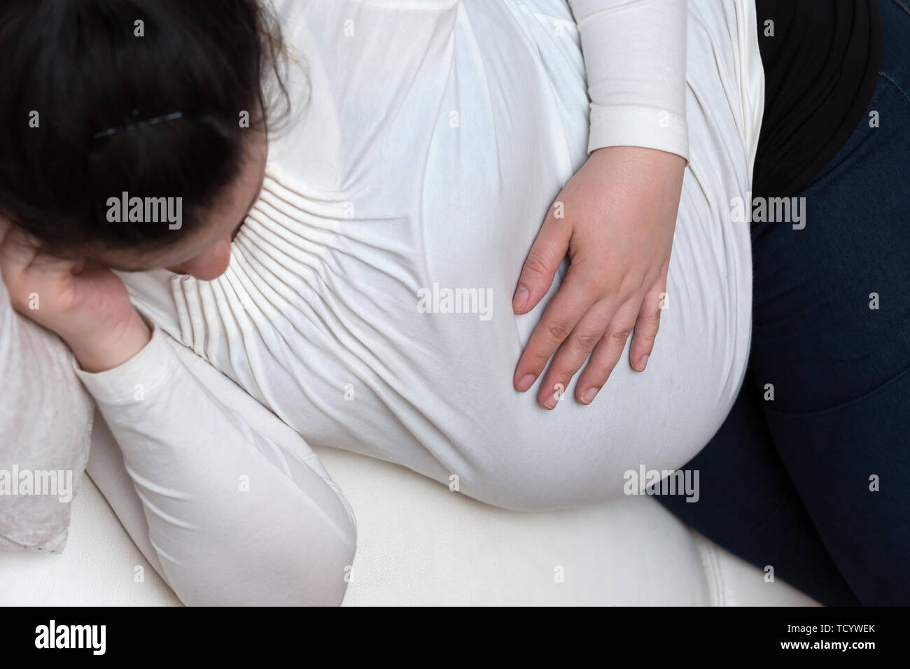Pregnant girl taking an afternoon nap on white couch Stock Photo - Alamy