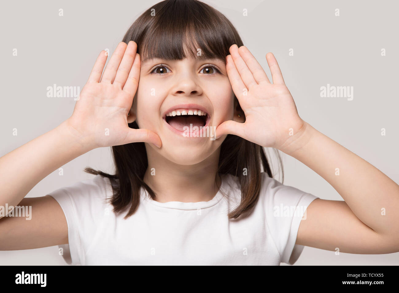 Little girl call somebody holding hands near face studio shot Stock ...
