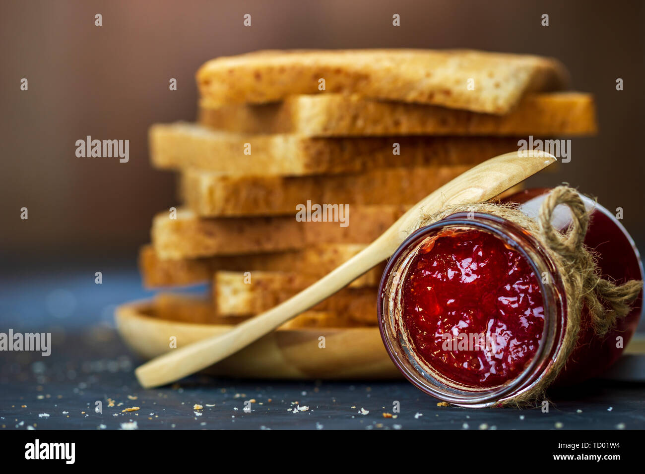 Strawberry jam bottle and whole wheat bread are stacked on a black ...