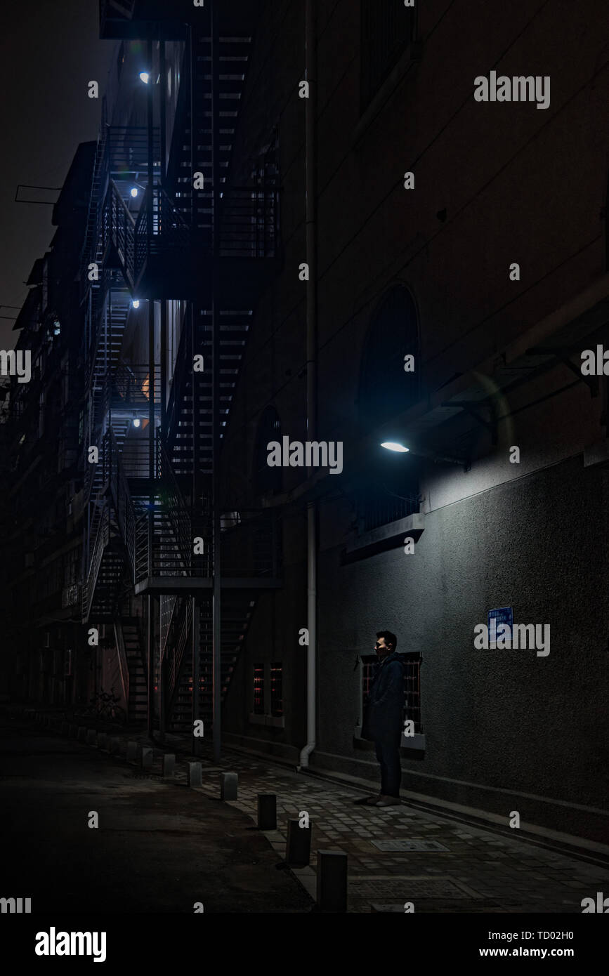 A man in the dim lights of a city street at night Stock Photo - Alamy