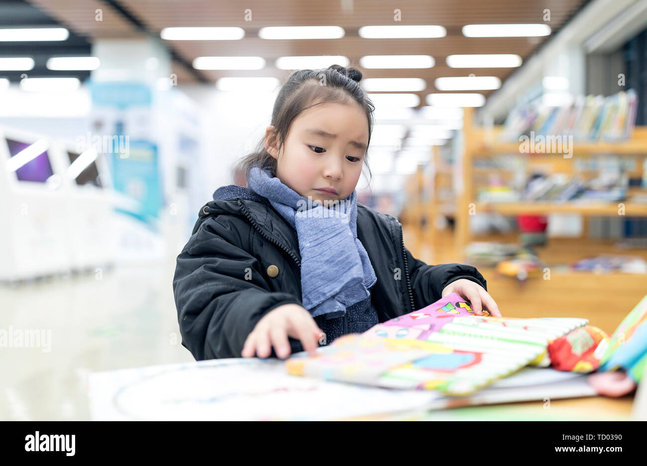 Little Asian girl reading in the library Stock Photo - Alamy